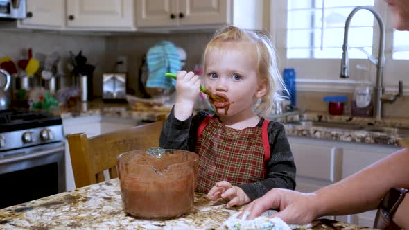 Adorable toddler girl eating chocolate pudding out of the mixing bowl ...