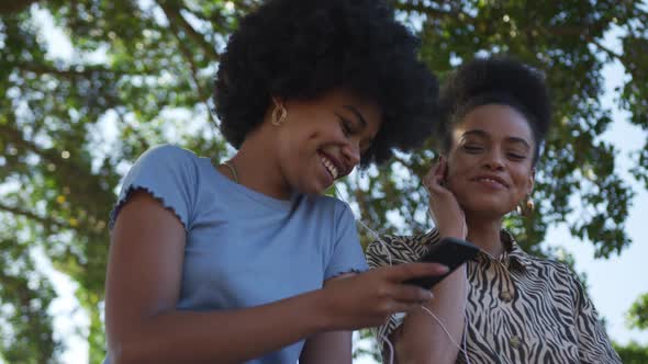 Two mixed race women listening music in park, Stock Footage | VideoHive
