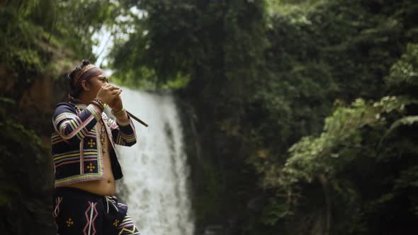 Indigenous person playing Kubing tribal instrument, behind is a ...