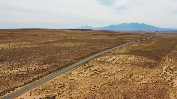 Car driving down a hot desert road with mountain background in Utah ...