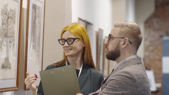 Female Gallery Docent Showing Artwork to Male Visitor, Stock Footage