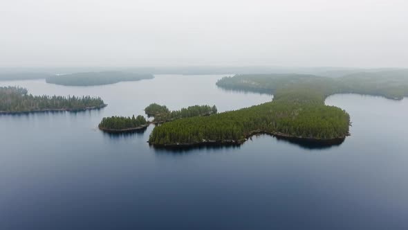 Drone approaching islands with forest in a lake with foggy horizon in ...