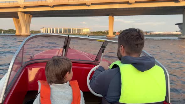 Father and Son Riding Motor Boat Wearing Safety Vests Having a Ride in ...