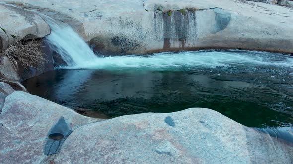 Panning right shot of waterfall flowing into a deep pool that spill out ...