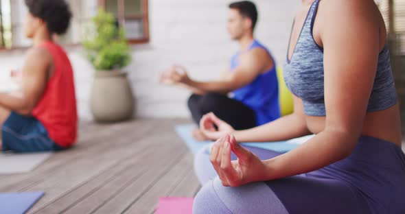 Midsection of biracial woman practicing yoga with group of diverse ...