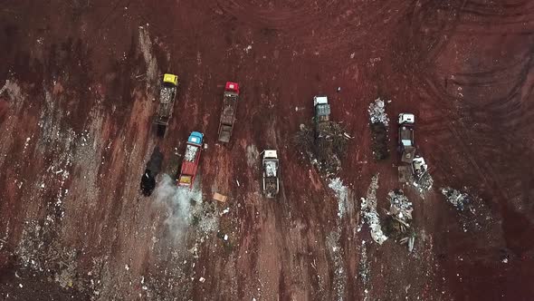 Straight down aerial view of dump trucks unloading garbage at a ...