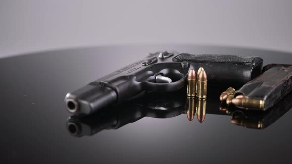 Gun Control. 9mm handgun with bullets rotating on a reflective surface ...