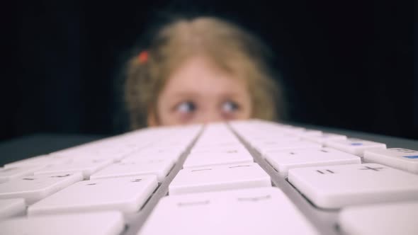 Blue Eyed Girl Hides Behind Table with Computer Keyboard, Stock Footage