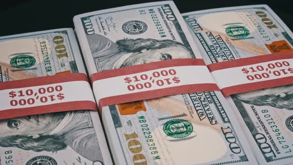 Three Stacks of 10000 American Dollars Banknotes in Bank Packs are Spin ...