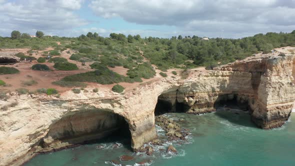 Drone pulling away from beautiful shoreline with caves and cliffs ...
