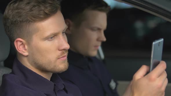 Two Patrolmen Sitting in Police Car, Chatting on Smartphones During ...