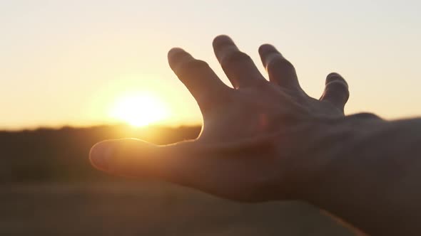 Male Hand Against Sunset. Touch the Sun. Sun Shines Through Fingers ...