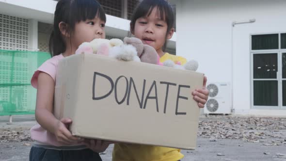 Cute sibling girls holding donation box with old dolls outdoors ...
