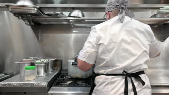 Back View of Woman Chef Cooking Food in the Kitchen of a Restaurant ...