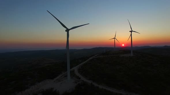 Aerial view of slowly rotating windmill blades at colorful sunset ...