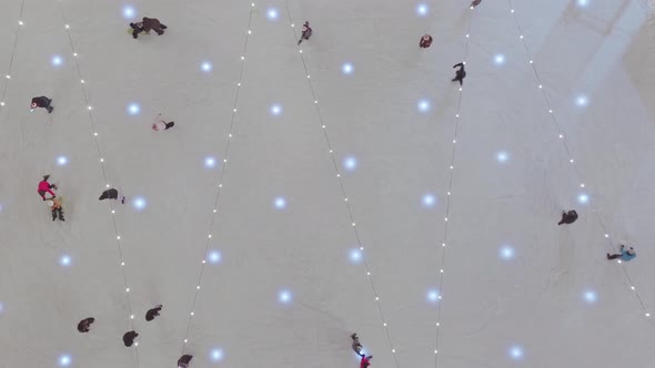 Aerial top-down view above festive lights and people skating on ice ...