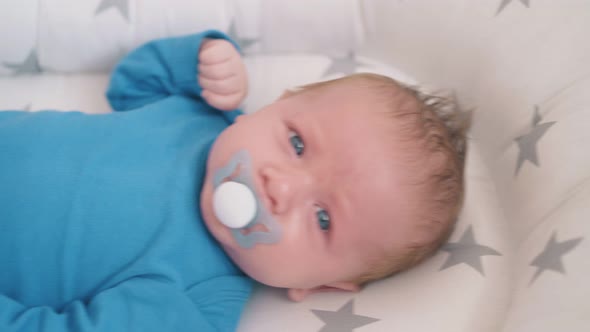 Sad Little Kid with Pacifier Lies in Sleeping Cocoon Closeup, Stock Footage