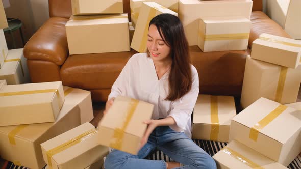 Top view of young Asian woman receive throwing boxes and sit among many ...