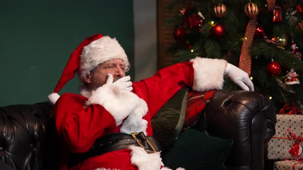 Tired Santa Claus Yawns and Falls Asleep Sitting on the Couch, Stock ...