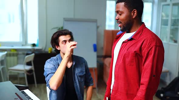 Italian Or Indian Teacher Practicing Vocal Cords With African American Man In Class Day Time