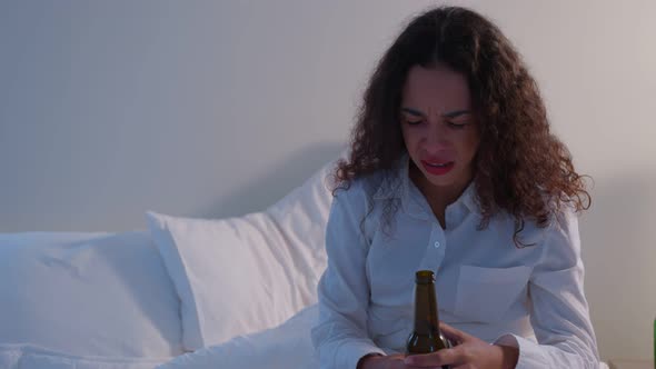 Drunk Latino woman hold beer bottle, and crying feel hangover on bed ...