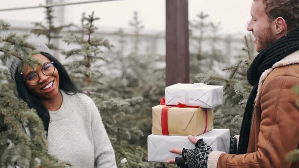 Happy Multiracial Couple Exchanging Gifts at Sprue Trees Market, Stock ...