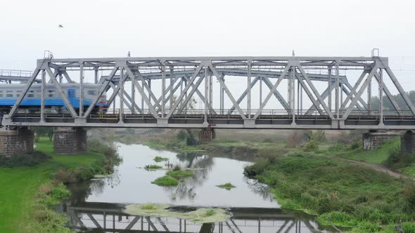 Electric train passes through the railway bridge across the river ...