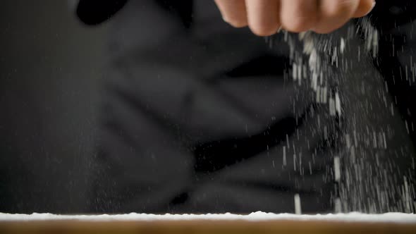 Cook Sprinkles Flour on Wooden Table on Black Background, Stock Footage