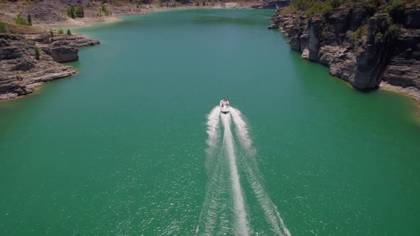 motor boat moves along a green river between rocky cliffs at summer ...