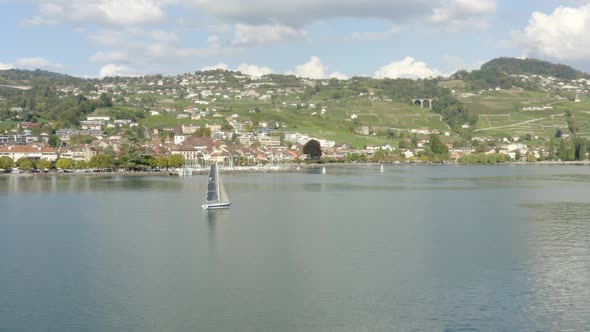 Flying by sailboat then overflying medieval town of Lutry and its port ...