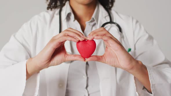 Video of biracial female doctor holding heart on white background ...