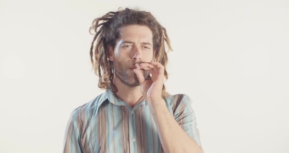 Man with dreadlocks smoking medicinal marijuana on white background ...