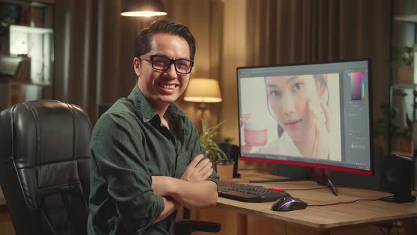 Asian Male Editor Works In Photo Editing Software. He Turns And Warmly ...