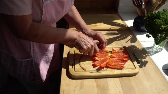 Senior lady cutting paprika in the kitchen on a sunny afternoon, Stock ...