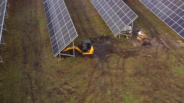 excavator digs under solar panels in the sun power plant, Stock Footage