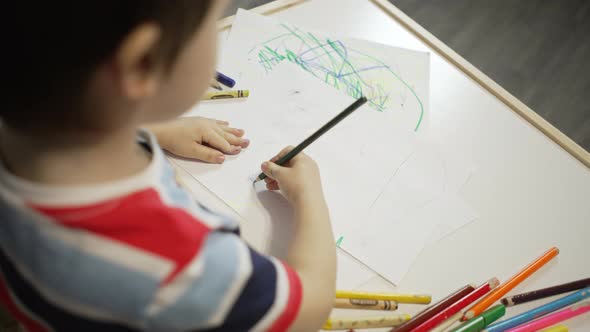 The Child Learns to Draw at the Children's Table with Colored Pencils ...