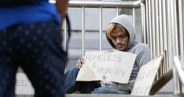 Homeless man sitting and holding homeless and hungry sign on the ...