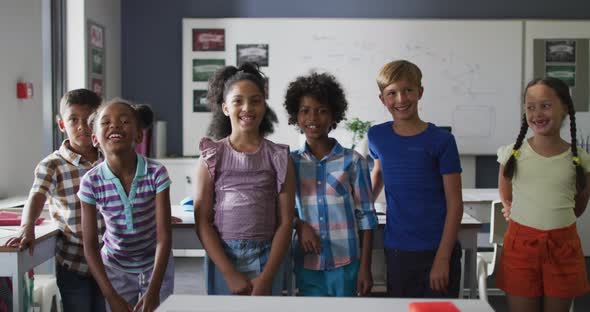 Video of happy diverse pupils jumping with joy in classroom, Stock Footage
