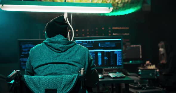 A Man in a Wheelchair a Hooded Hacker Works on a Computer with Data ...