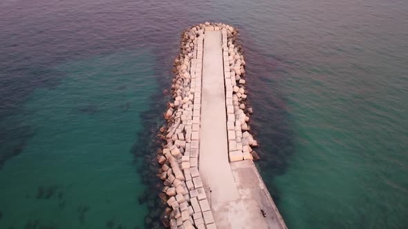 Aerial view of stony jetty surrounded by crystal clear ocean water ...