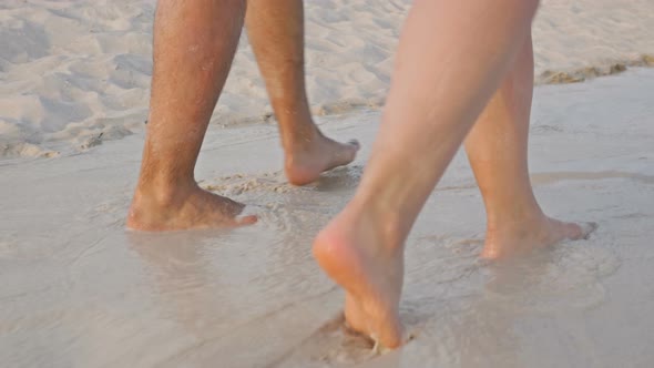 Man and Female Legs Wandering on the Water on the Beach., Stock Footage