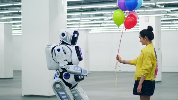 Young Lady Is Offering Colourful Balloons To a Cyborg, Stock Footage