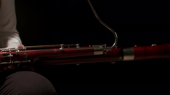 Woman sitting on chair in studio with bassoon on her lap picks it up ...