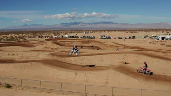 Two motocross racers jumping over ramp in Mojave Desert landscape track ...