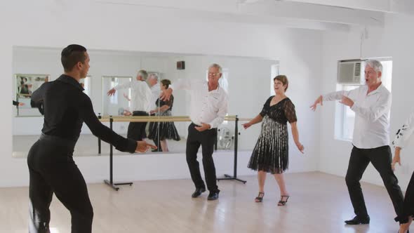 mixed race male dance teacher taking a ballroom dancing class at a ...