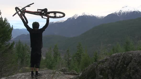 A mountain biker lifting bike over his head in celebration, Stock Footage