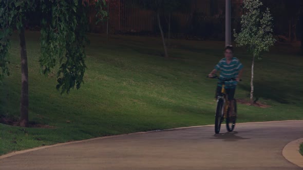 Two kids riding thier bike in a park at night, Stock Footage | VideoHive