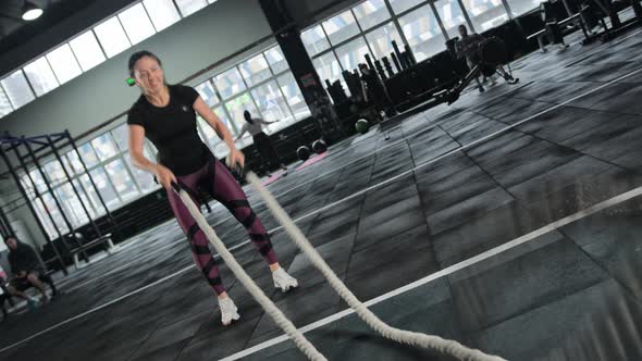 Young female athlete trains in the gym with ropes, crossfit, endurance ...