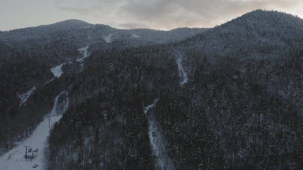 Flying up the ridge of a snow dusted mountain with a broken ski lift ...