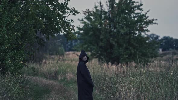 Field with ghost in countryside. Spooky field with ghost in black cloak ...